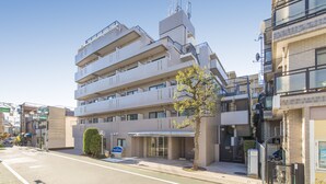 Um hotel de vários andares com design moderno, com varandas, uma entrada central e uma área de estacionamento.