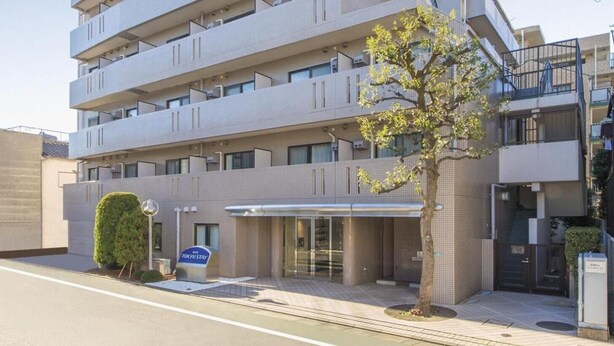 Um hotel de vários andares com design moderno, apresentando varandas em cada andar, uma entrada visível e uma placa indicando ser propriedade TOKYU STAY.