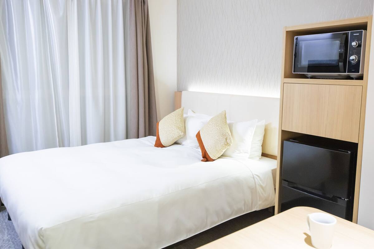 Quarto de hotel com uma cama, micro-ondas e frigorífico.
