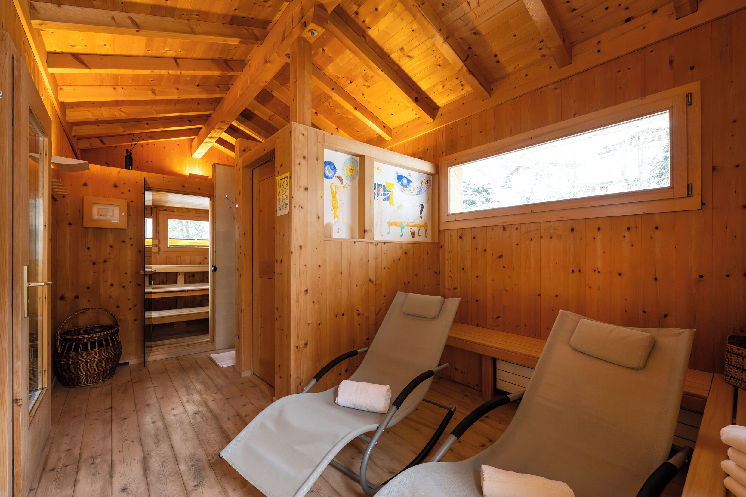 Uma cabana de madeira com duas poltronas reclináveis, uma janela e uma porta que dá para uma varanda.