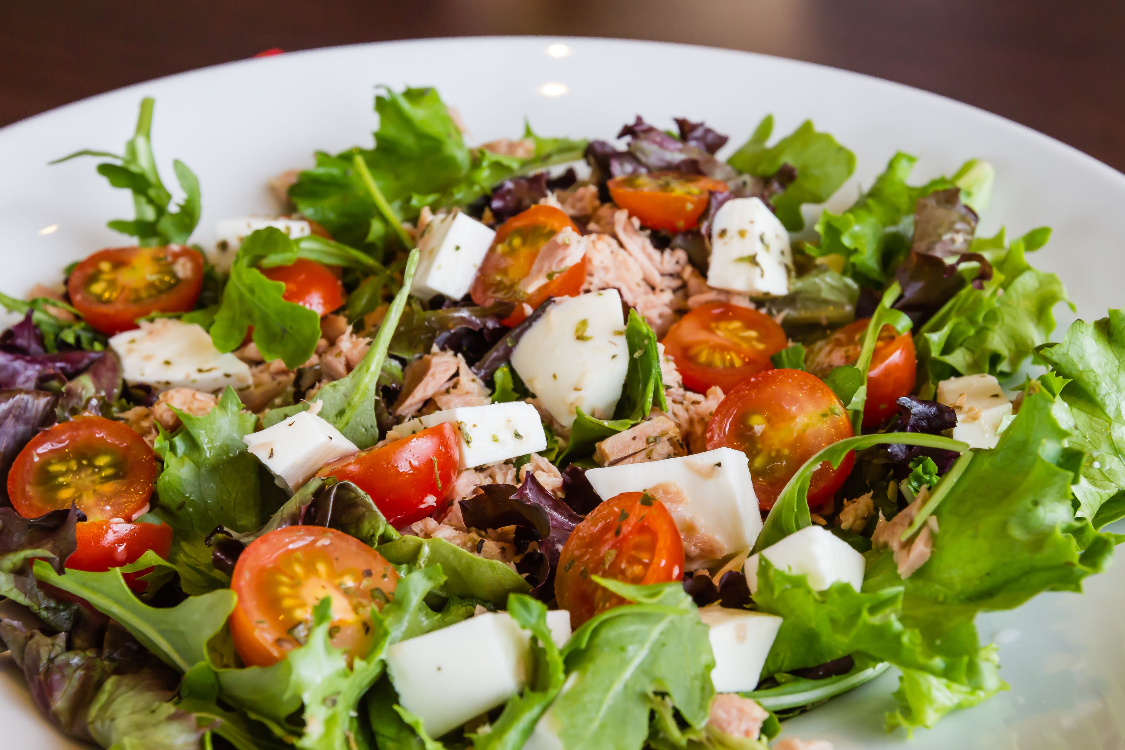 Prato de salada de folhas verdes mistas com tomate, queijo e atum.