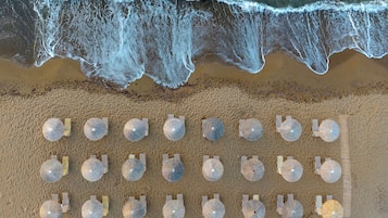 Na praia, espreguiçadeiras, guarda-sóis de praia, toalhas de praia