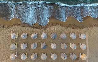 Na praia, espreguiçadeiras, guarda-sóis de praia, toalhas de praia 