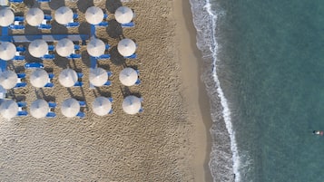 Na praia, espreguiçadeiras, guarda-sóis, toalhas de praia