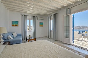 Quarto de hotel com uma cama grande, um sofá, uma mesa pequena e uma varanda com vista para o mar.