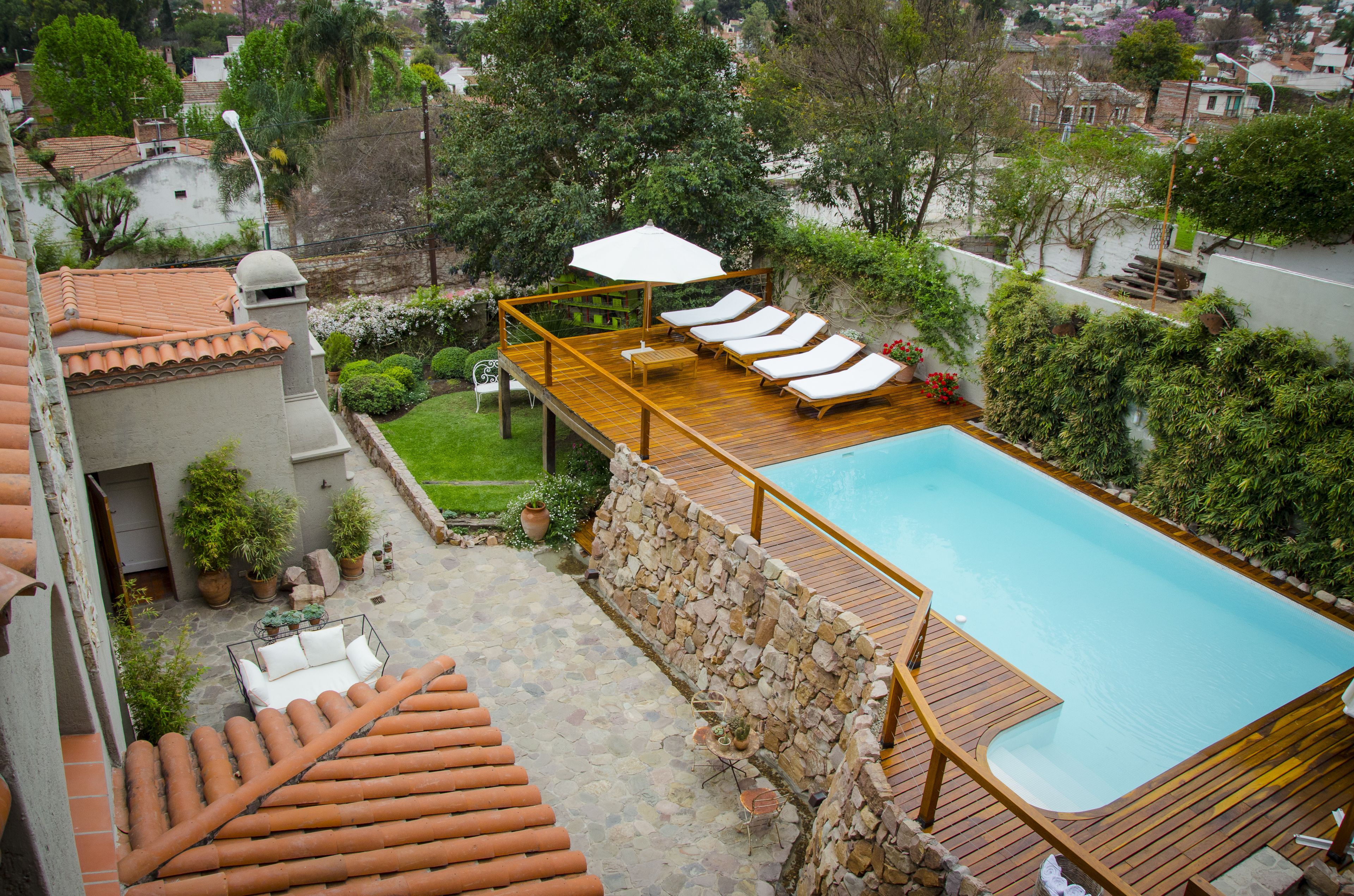 Piscina no terraço com espreguiçadeiras e um muro de pedra.
