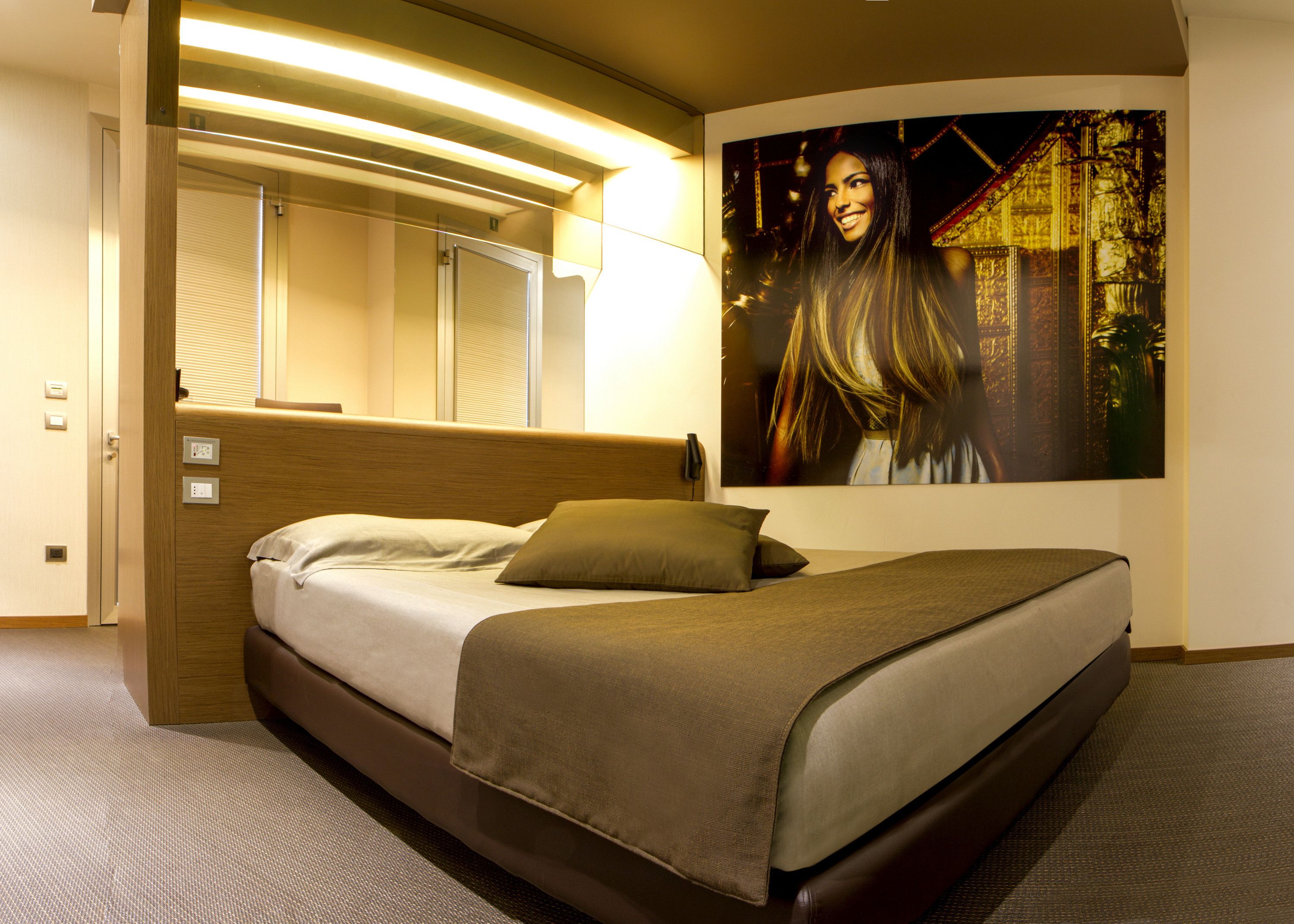 Quarto de hotel com cama, uma janela ampla e uma obra de arte na parede.