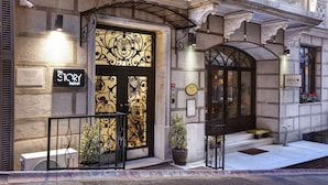 Entrada de hotel com detalhada ferragem, um letreiro com o texto "The Story Hotel" e uma placa indicando o nome do hotel.