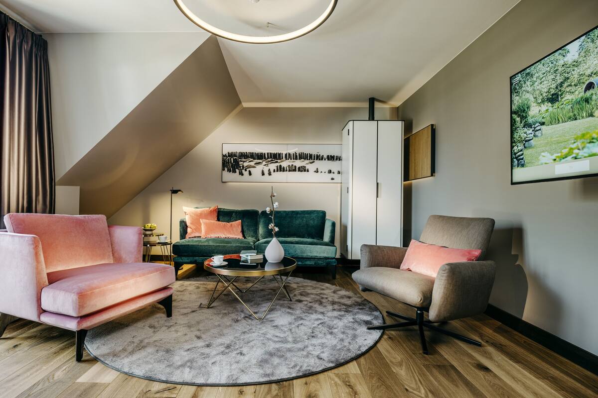 Uma sala de estar moderna com uma mesa de centro redonda, duas poltronas, um sofá e uma tela de TV grande.
