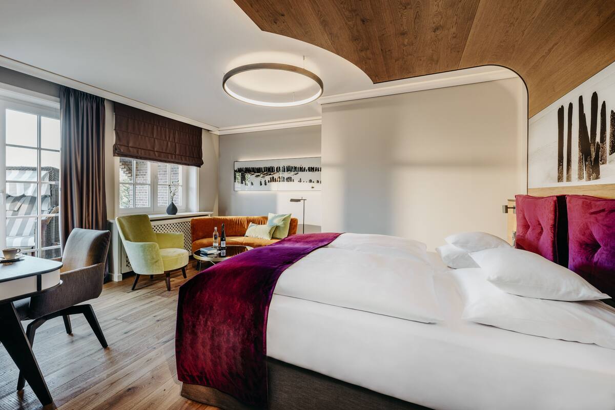 Quarto de hotel com cama, escrivaninha, cadeira e sofá.