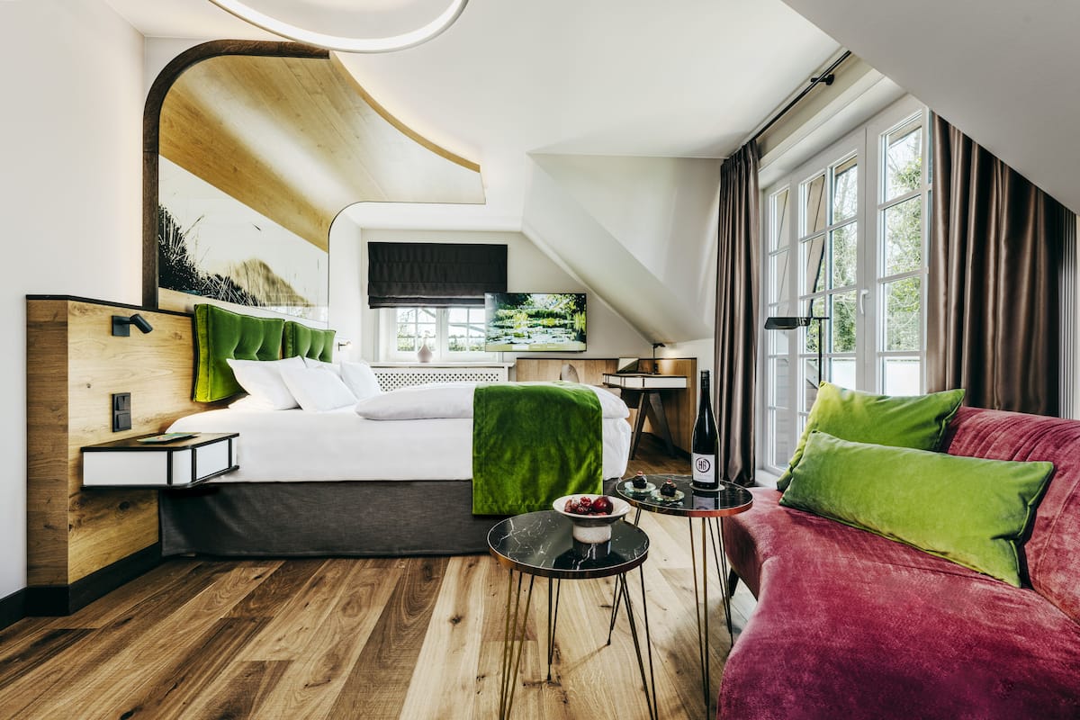 Quarto moderno com cama, sofá vermelho, mesa pequena e televisão.