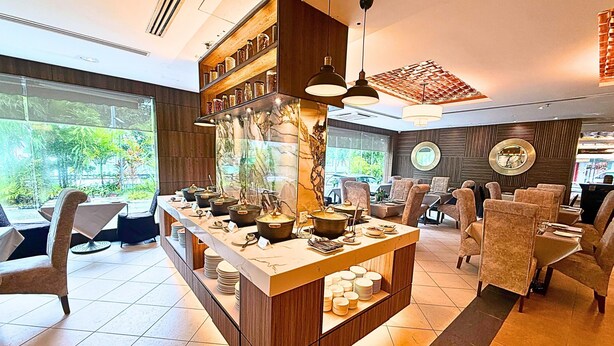 Restaurante moderno com ilha central, mesas e cadeiras.