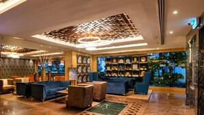 Um hall moderno com área de estar, parede com objetos emoldurados e teto decorativo.