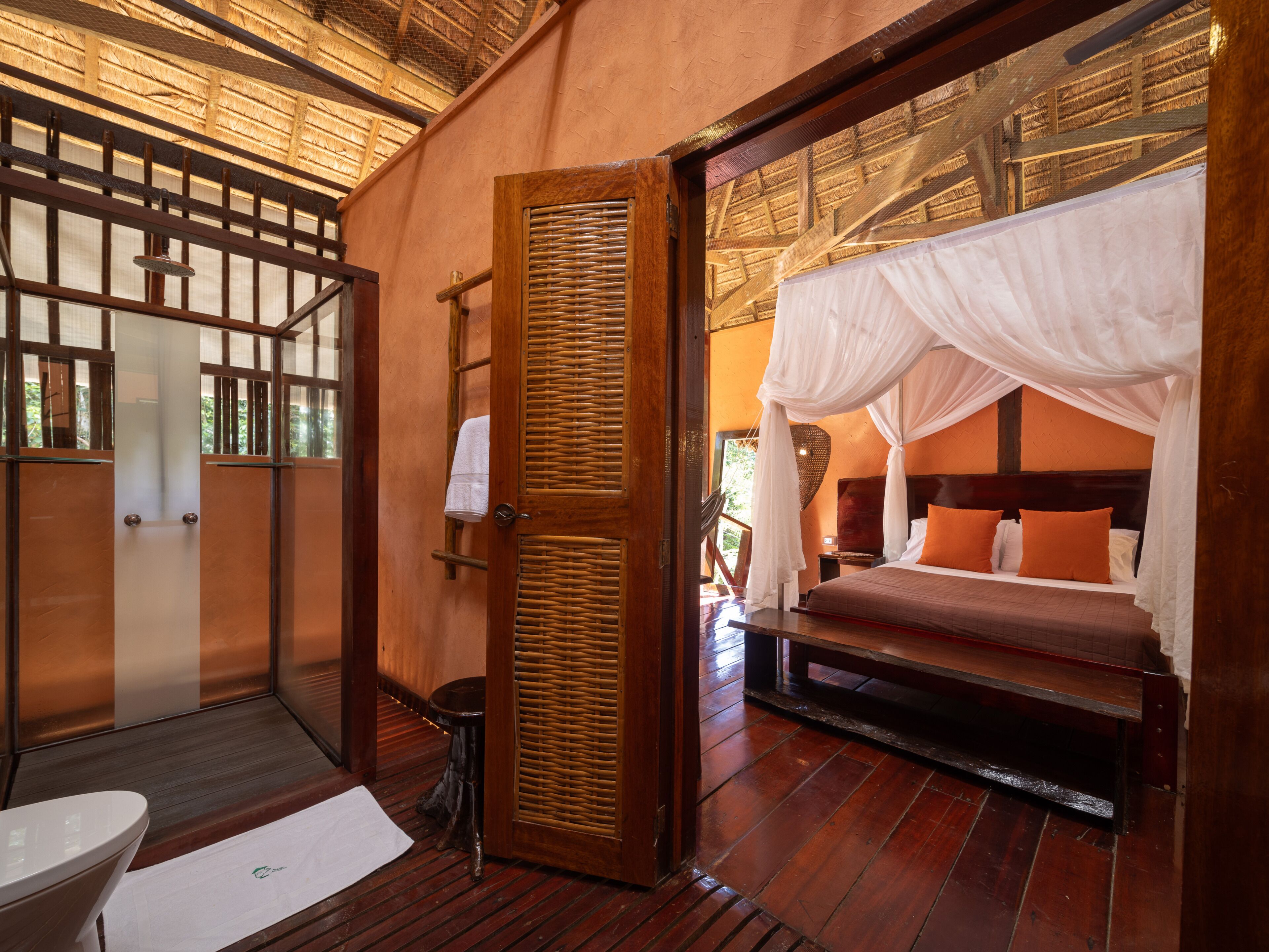 Quarto de madeira com uma cama, um sanitário e área de chuveiro.