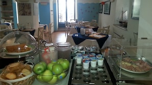Um buffet de café da manhã com diversos alimentos e uma grande janela ao fundo.