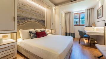 Quarto de hotel com uma cama grande, uma escrivaninha e vista para o exterior.