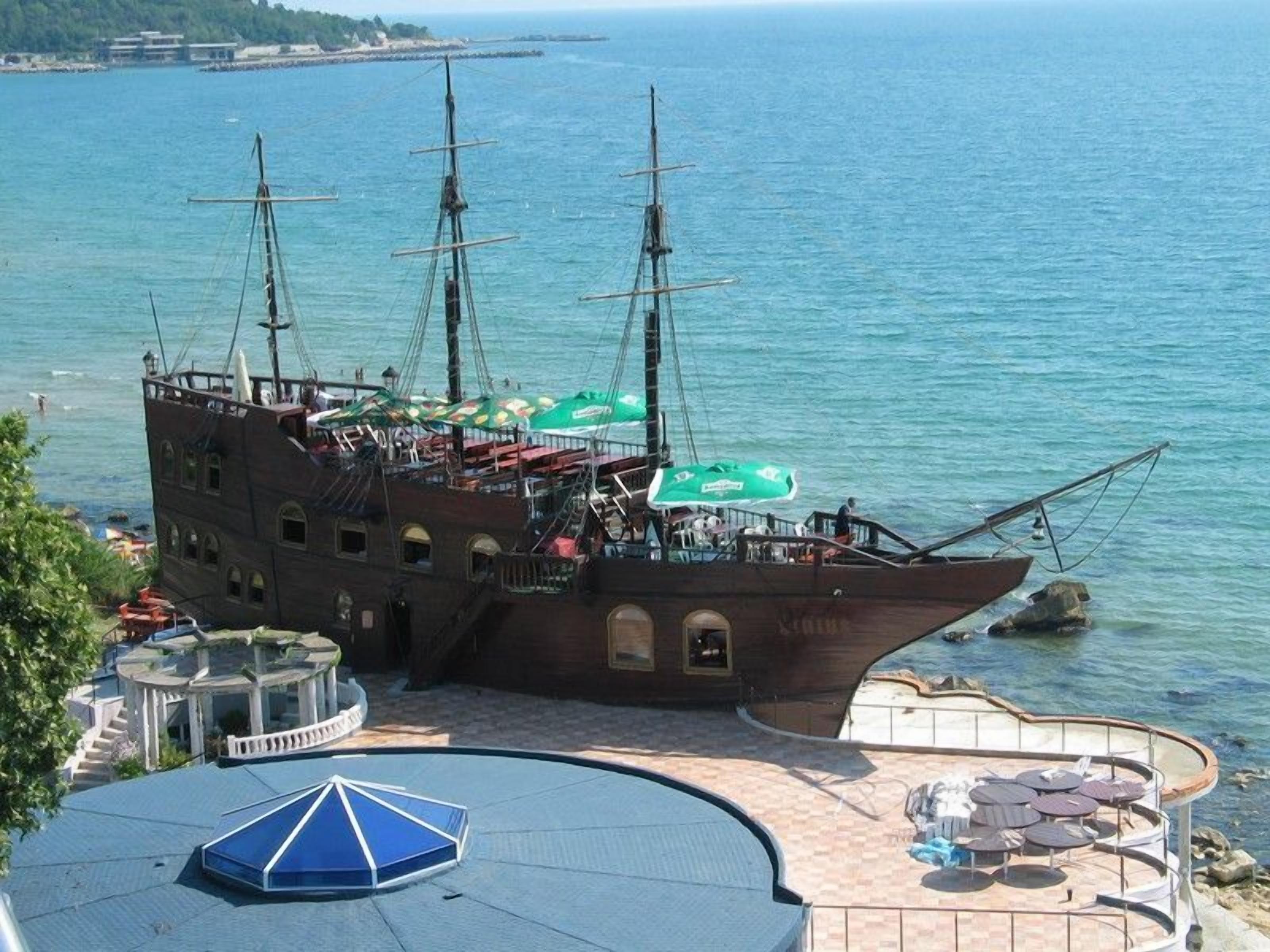 Restaurante com tema de pirata e mesas ao ar livre com vista para o mar.