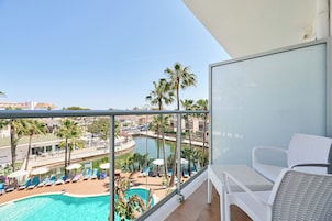 Varanda com vista para a piscina, cadeiras de vime branco e céu claro.