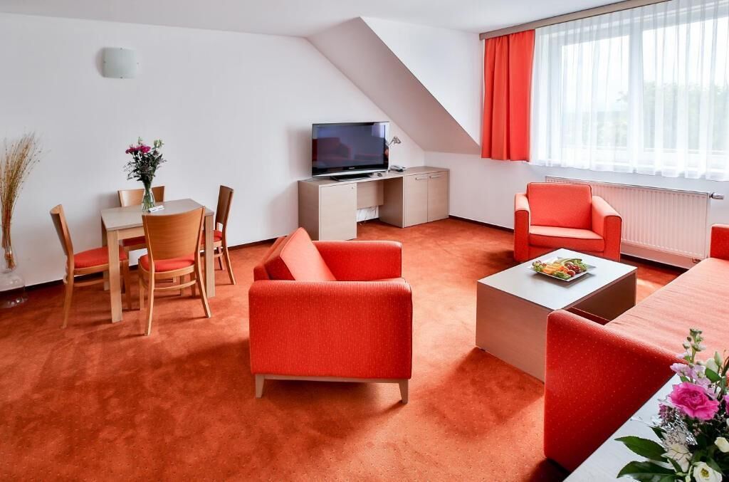 Uma sala de estar moderna com televisão, mobiliário vermelho e um espaço de refeições.