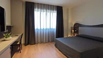 Quarto de hotel moderno com uma cama, uma mesa de escritório e uma televisão.