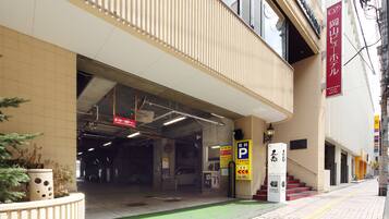 Entrada de hotel com rampa que leva à porta, placa de estacionamento e escadas.