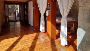 Corredor com piso de madeira que leva a um quarto com cama e cortinas brancas.