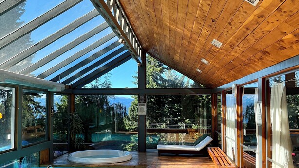 Um deck de madeira com piscina, bancos e ofurô.
