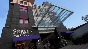 A modern building with a glass entrance, a sign reading "SERLA KUTA RALI," and a statue of an elephant.