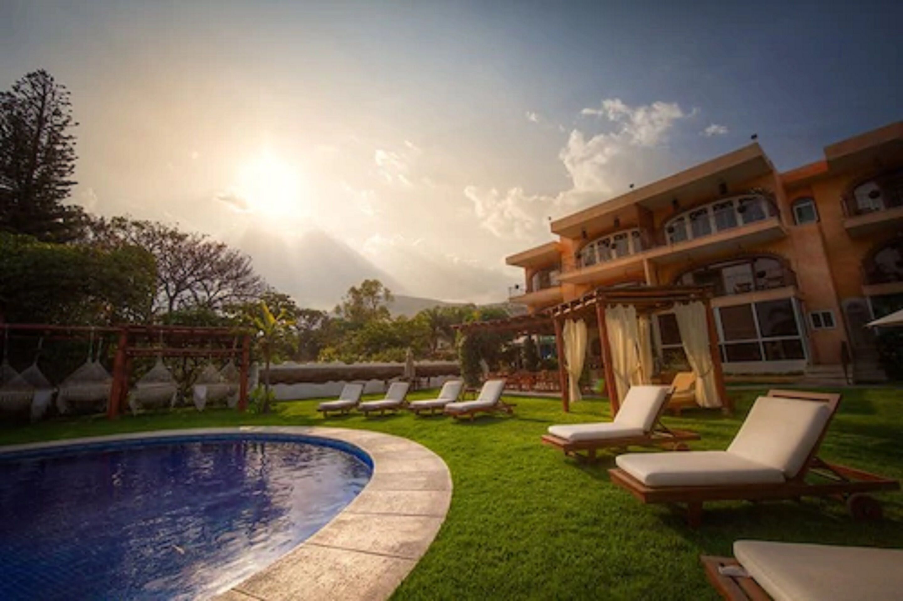 Uma área de piscina com espreguiçadeiras e um edifício com várias varandas.