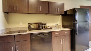 Cozinha com armários de madeira escura, geladeira preta, lava-louças e micro-ondas.