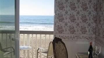 Quarto com vista para o oceano, uma mesa de jantar com cadeiras e uma garrafa de vinho.