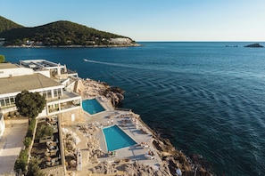 Um hotel à beira-mar com piscina, área de estar ao ar livre e vista para o mar.