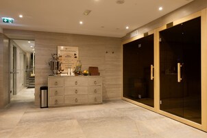 Uma área de spa com um balcão de recepção, um sinal que lista as 5 melhores massagens e uma porta de vidro que dá para uma sauna.
