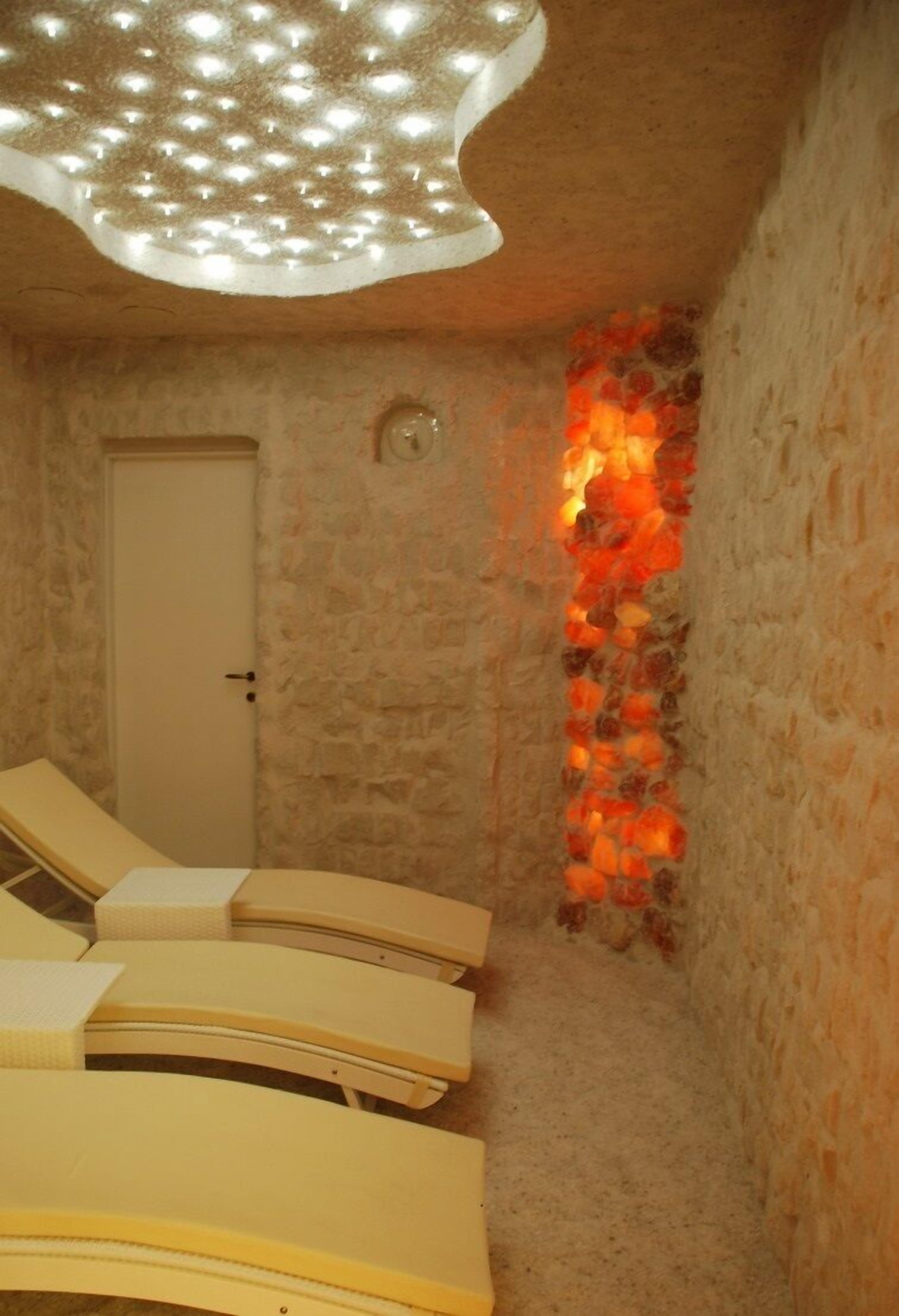 Um espaço de spa com paredes de pedra, luminária no teto e uma porta.