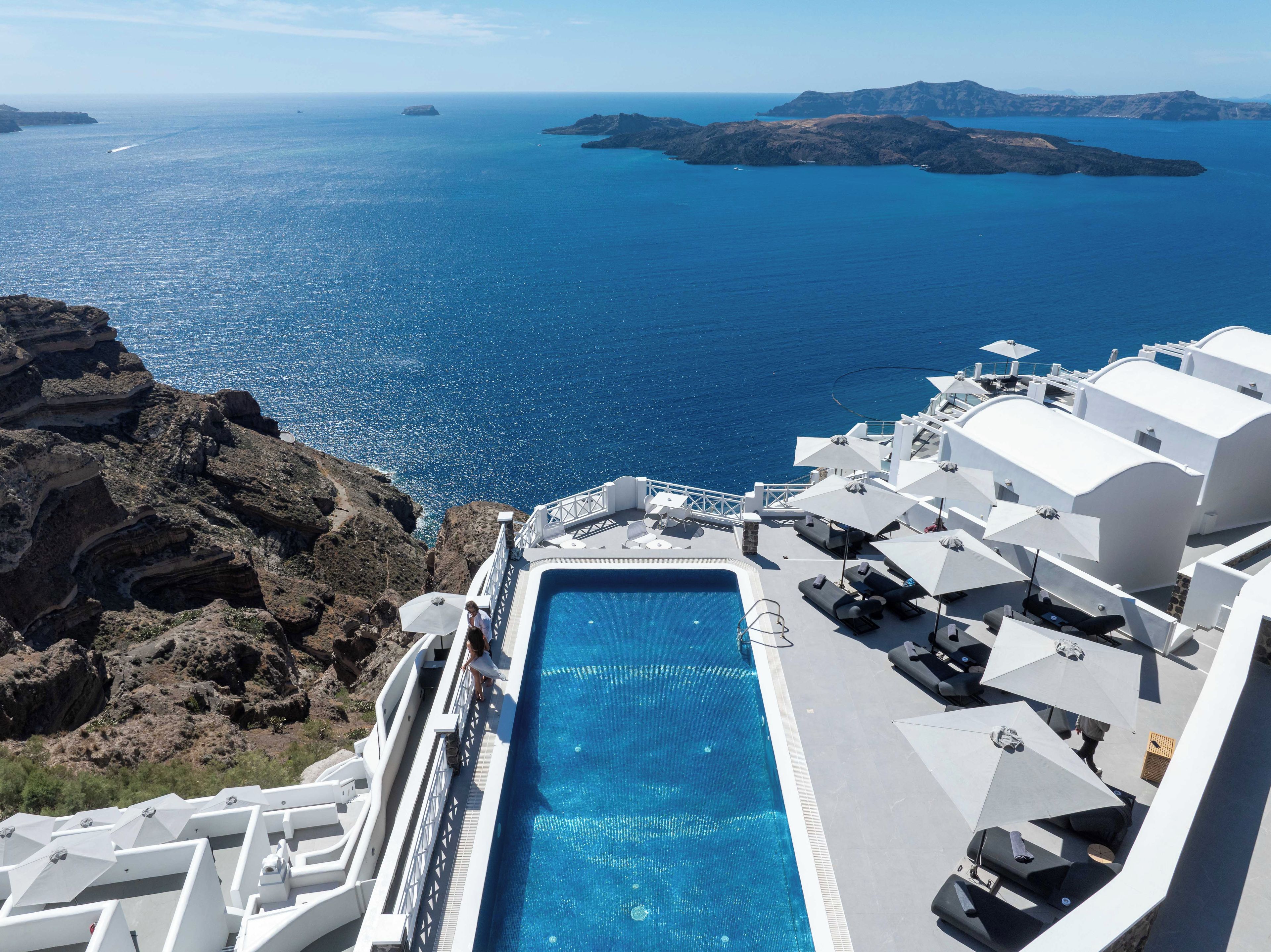 Piscina com vista para o mar e relevo rochoso.