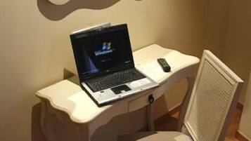 Um laptop sobre uma mesa branca, com um espelho acima.