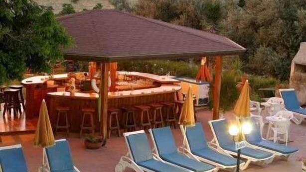 Uma área de bar com banquetas e um espaço de lounge à beira da piscina, com espreguiçadeiras e guarda-sóis.