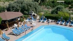 Piscina com espreguiçadeiras e área coberta.