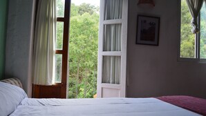 Quarto com uma grande janela, uma cama e uma moldura na parede.