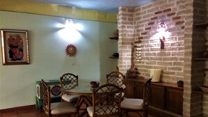 Uma sala de jantar com uma mesa redonda e quatro cadeiras, um relógio de parede e um objeto decorativo na parede.