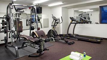 Uma academia com equipamentos de musculação, esteiras e colchonetes.