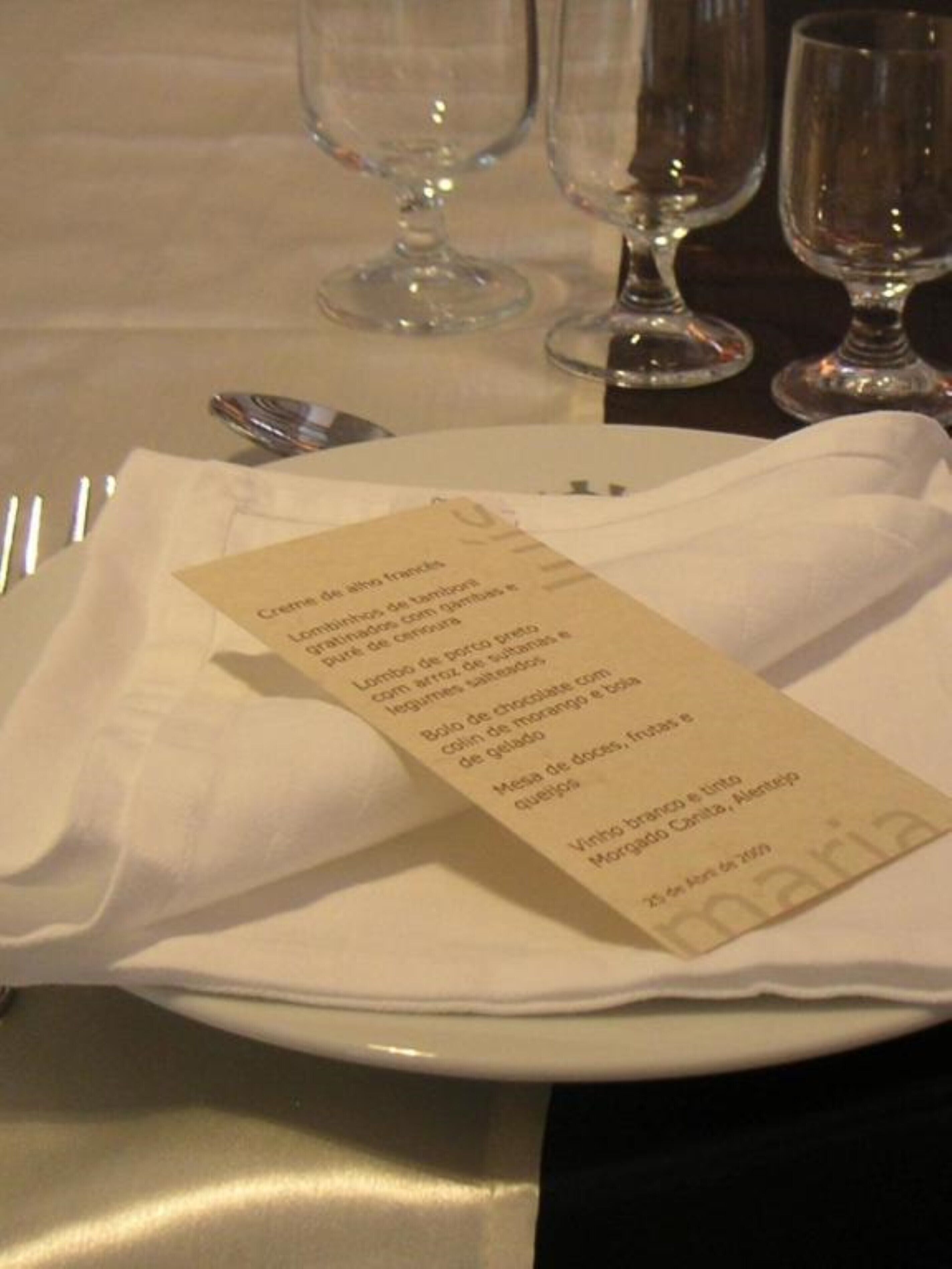 Uma mesa posta com um cardápio, copos e talheres.