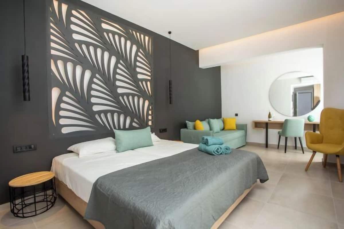 Quarto moderno com cama, mesa de cabeceira e um espaço de estar com sofá e cadeiras.