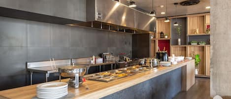 Cozinha moderna com ilha central, eletrodomésticos de aço inoxidável e iluminação pendente.