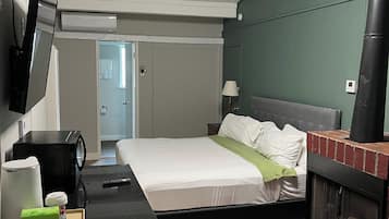 Quarto com cama, televisão na parede, lareira e secretária de madeira com micro-ondas e chaleira.