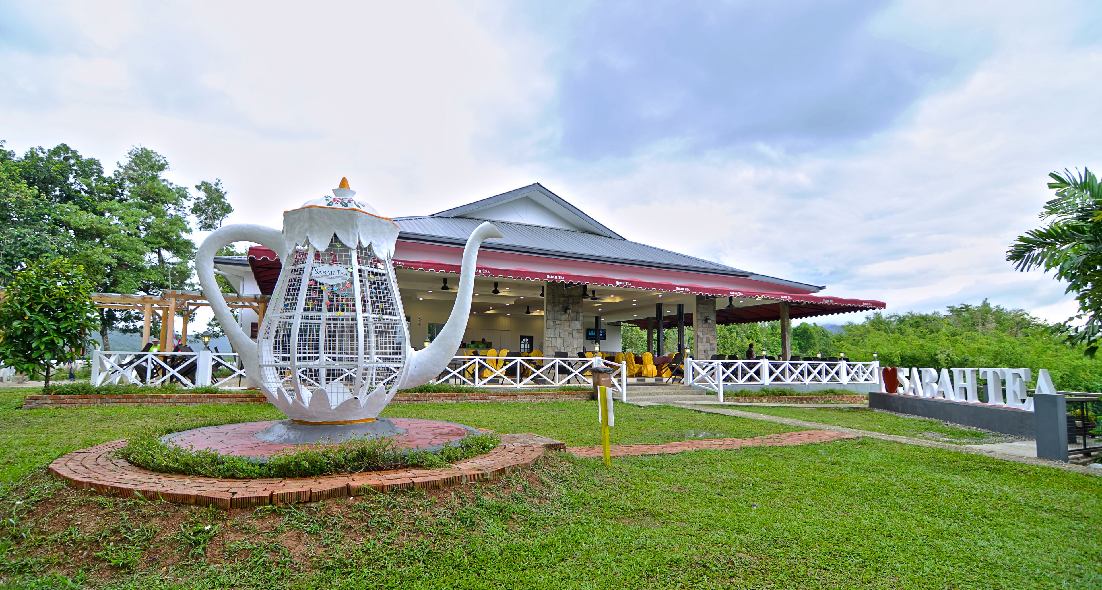 Um edifício com telhado vermelho e uma placa que diz 'SABAH TEA'.