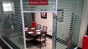 Espaço de negócios com mesa de conferência, cadeiras e um armário vermelho.