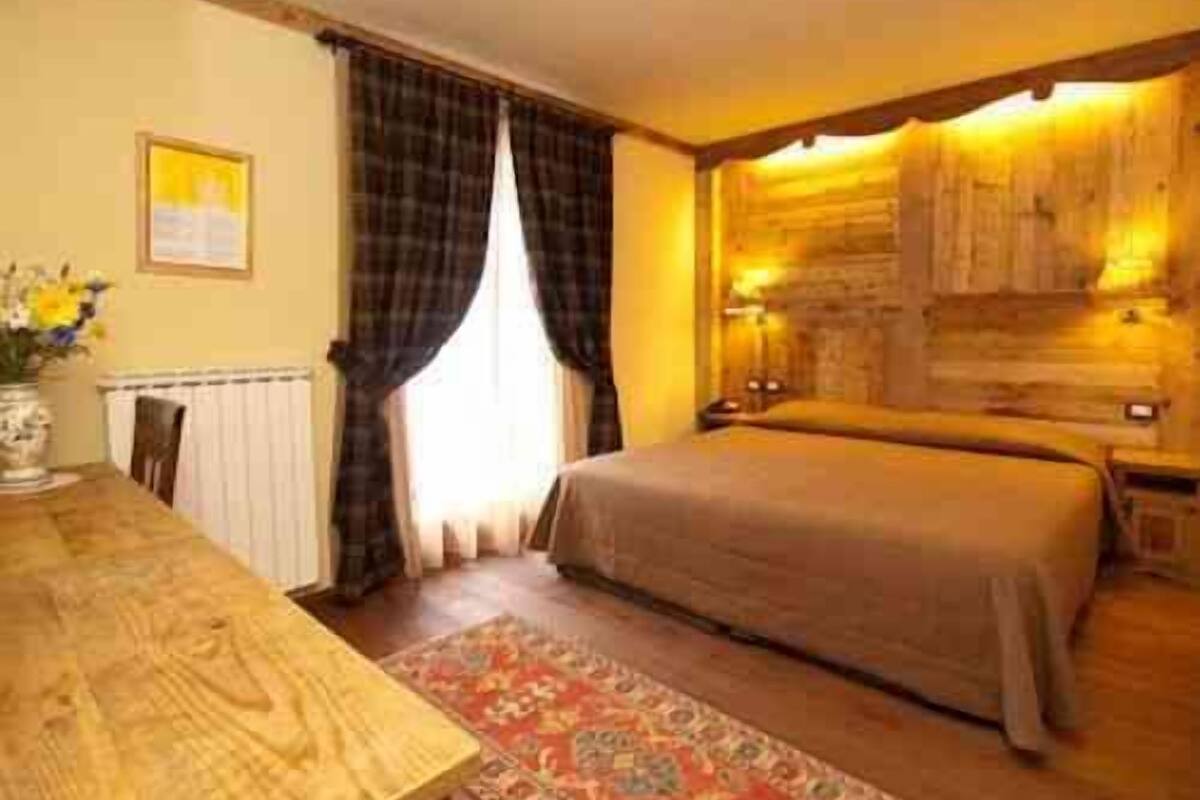 Quarto com cama de madeira, uma mesa de madeira e tapete estampado.