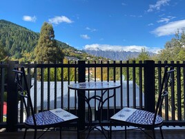 Varanda com duas mesas e cadeiras de mosaico, com vista para uma paisagem montanhosa sob um céu claro.