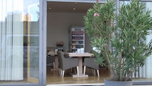 Um edifício moderno com entrada de vidro, uma máquina de café e um vaso de planta em primeiro plano.